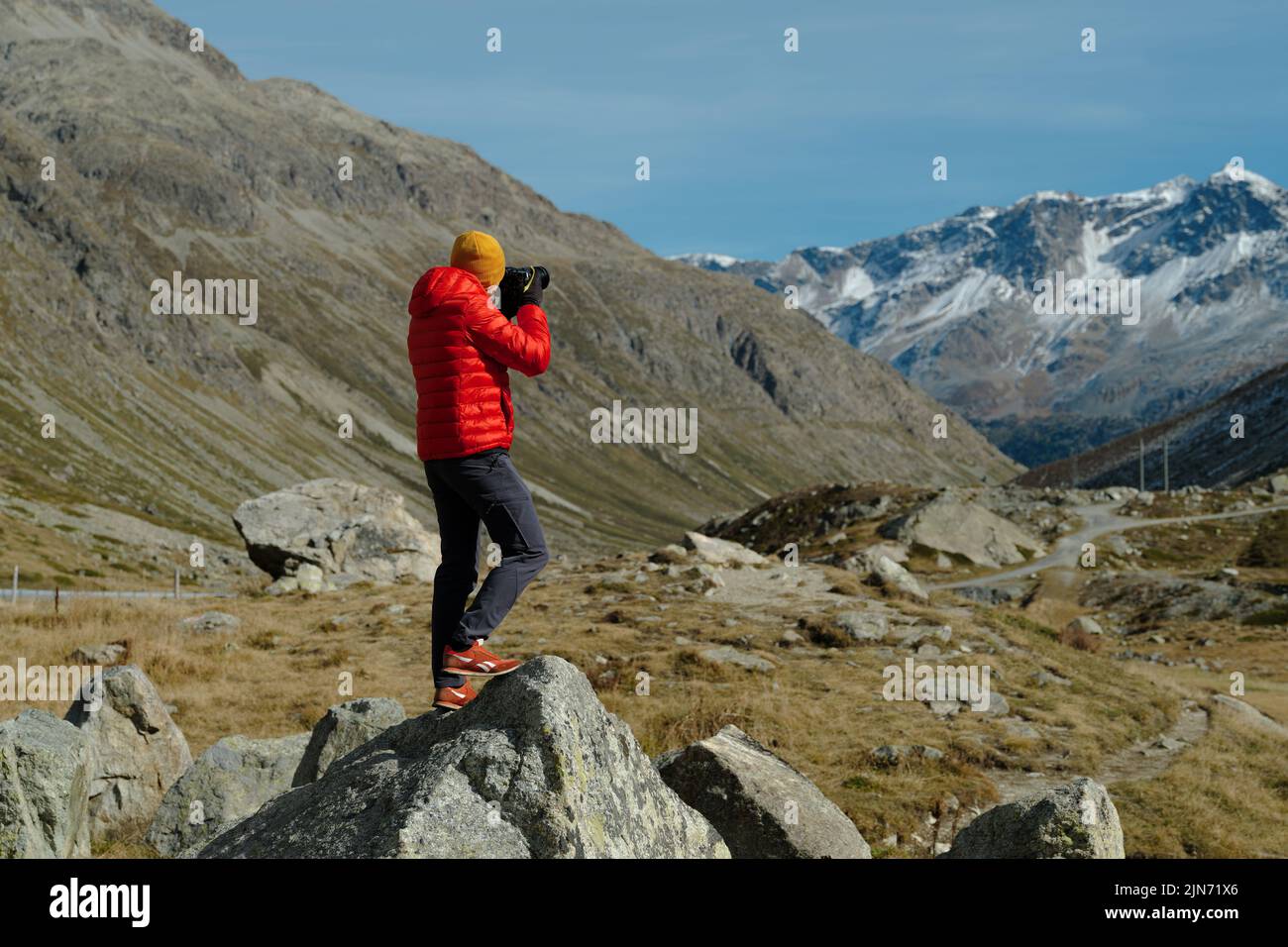 Back view of a tourist man in red jacket and camera standing with a ...