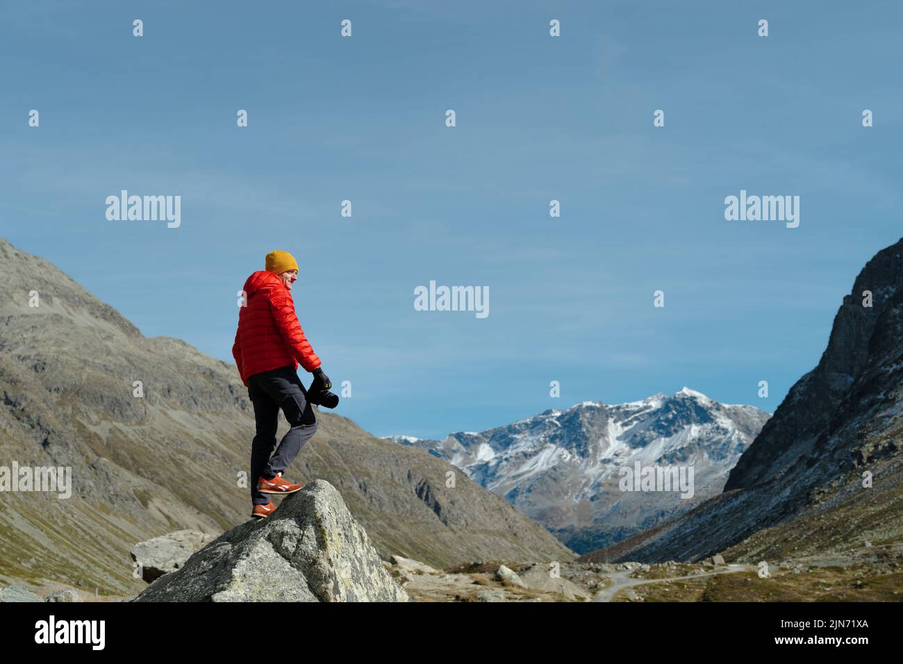 Back view of a tourist man in red jacket and camera standing with a ...