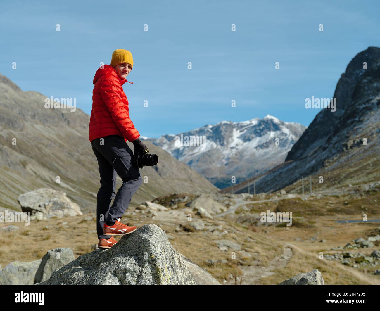 Back view of a tourist man in red jacket and camera standing with a ...