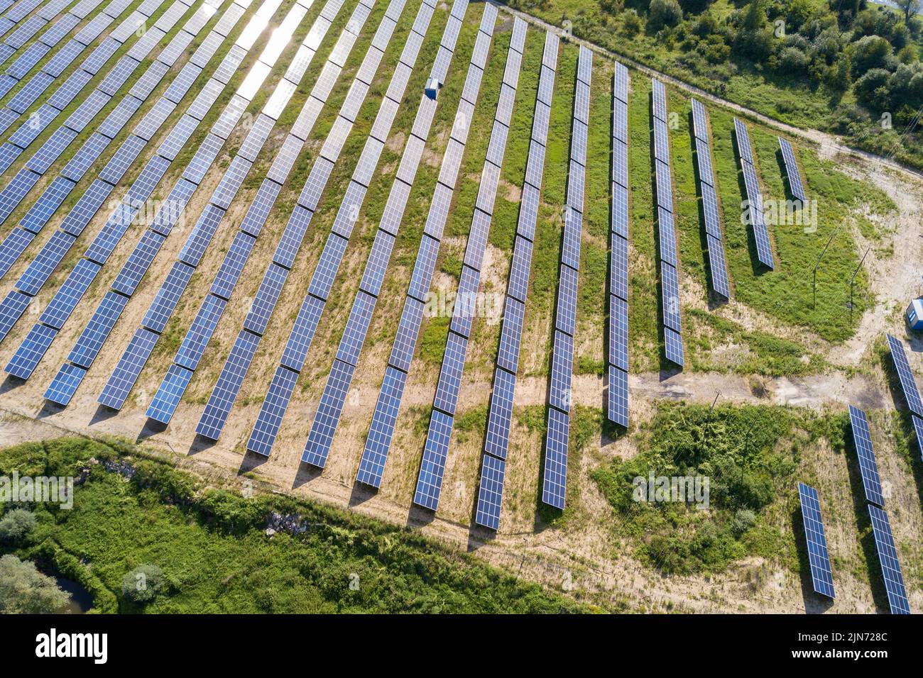 Aerial view of solar power plant on green field. Electric farm with panels for producing clean ...