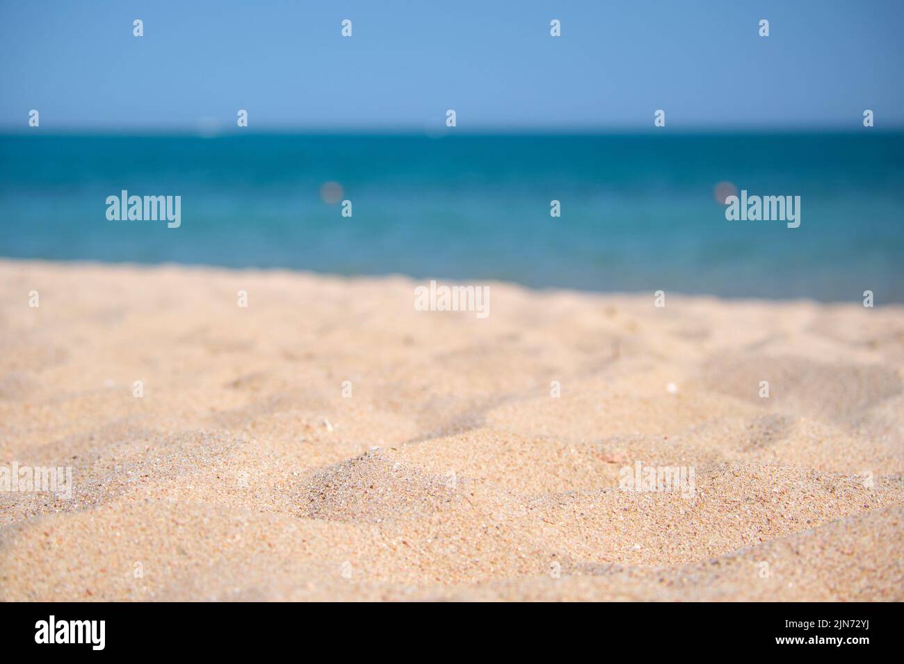 Close up of clean yellow sand surface covering seaside beach with blue ...