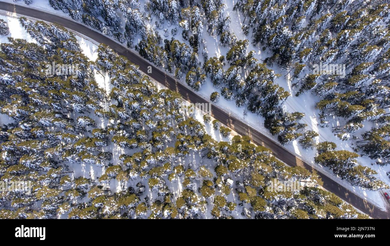 Aerial view of snowy winter landscape with drone, road passing through ...