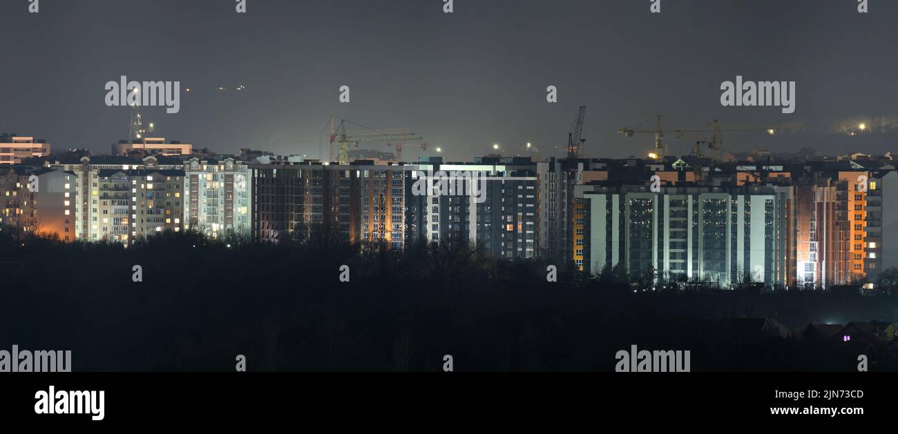 Dark silhouette of tower cranes at high residential apartment buildings ...