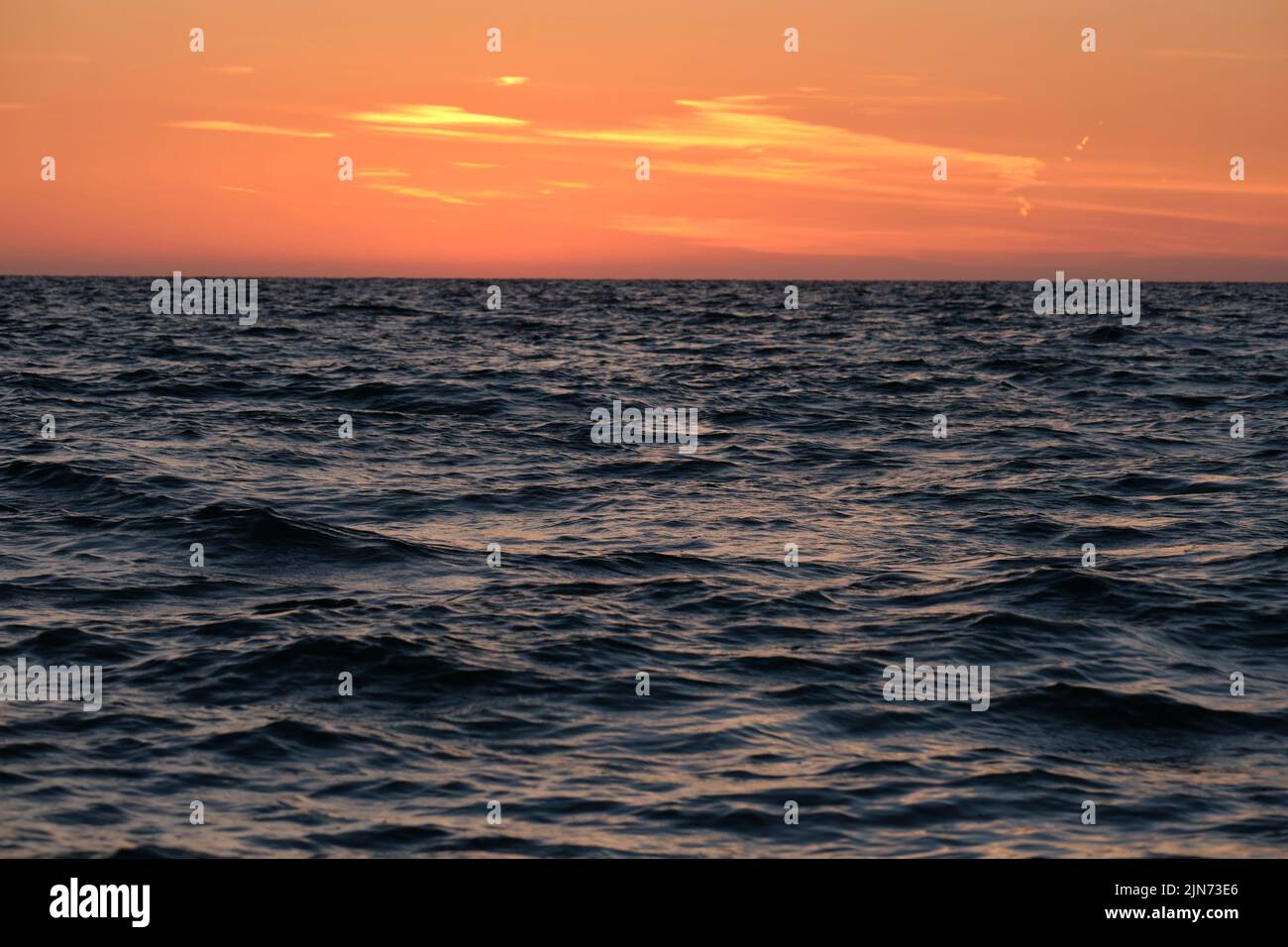 Dramatic bright red sky at ocean sunset, soft evening clouds over sea ...