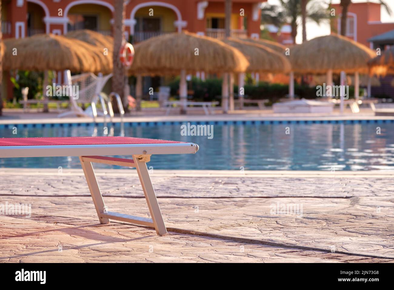 Empty deck chair on swimming pool side in summer resort. Vacations and ...