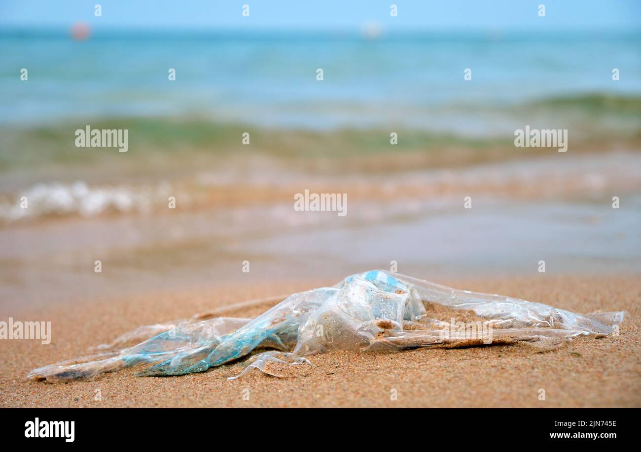 Left behind plastic bag garbage on sandy beach. Empty used dirty litter ...