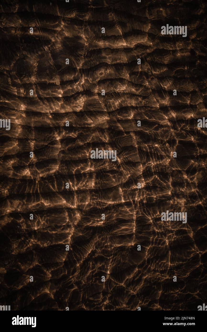 Clear sea water with dark brown sand beach background and sunlight that ...