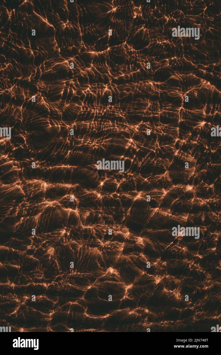 Clear sea water with golden brown sand beach and sunlight that reflects ...