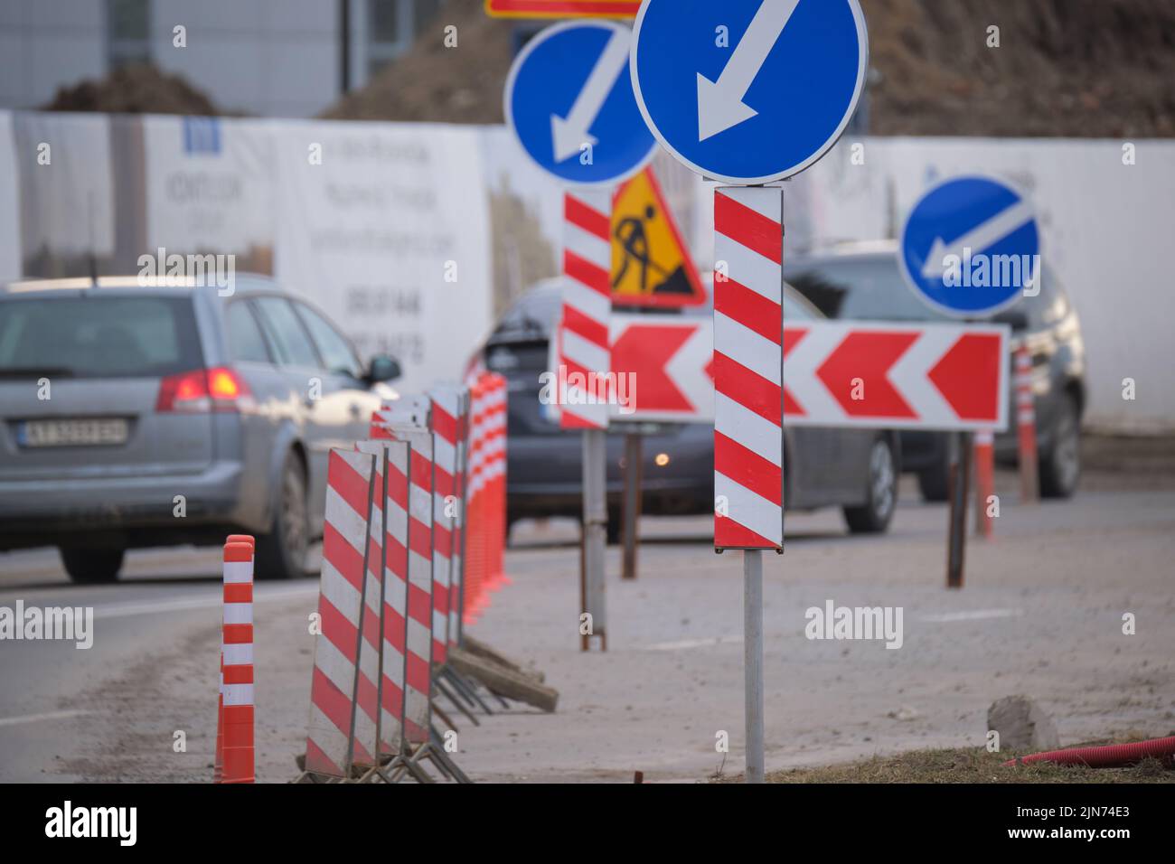 Roadworks warning traffic signs of construction work on city street and slowly moving cars Stock ...