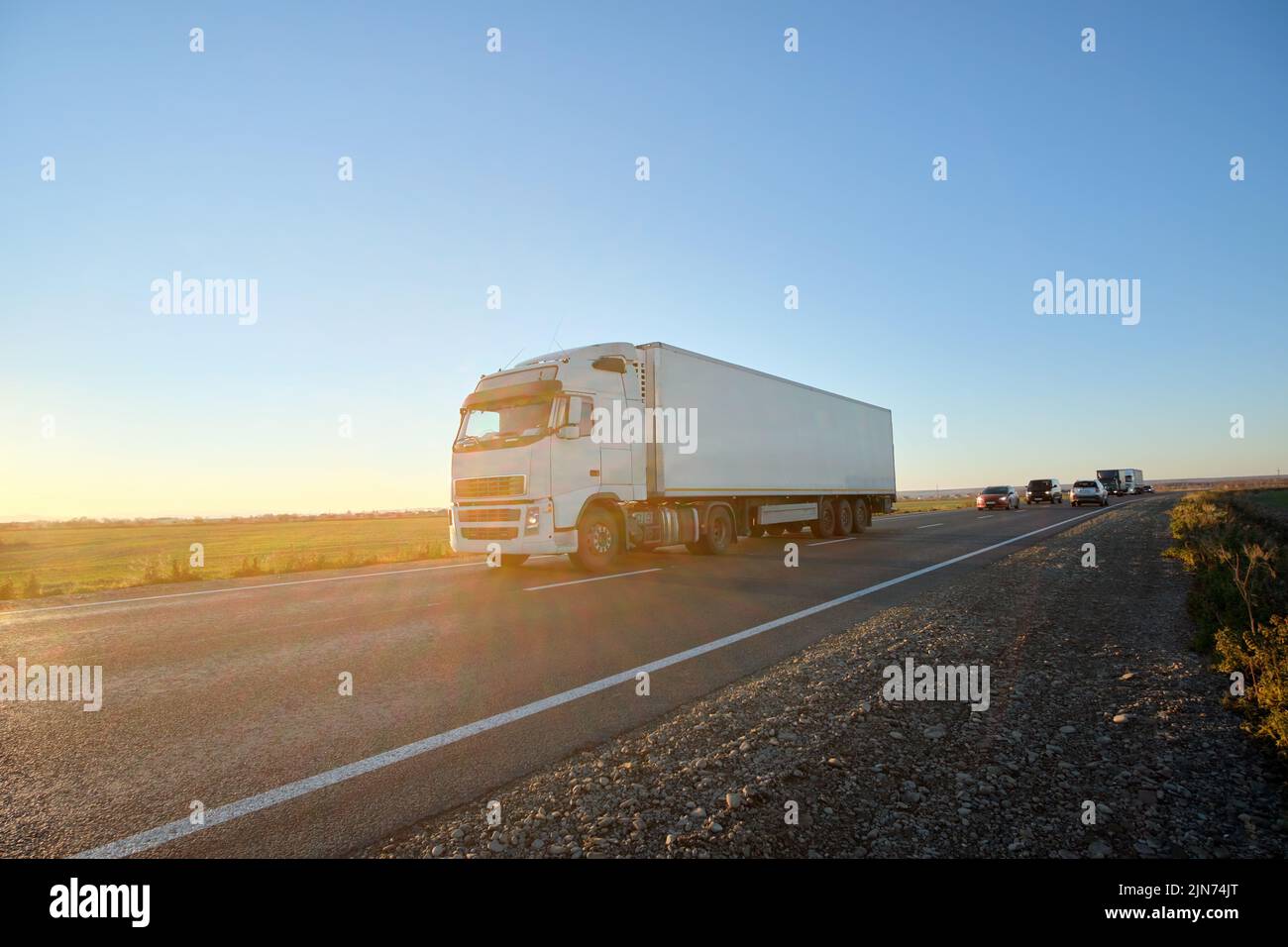 Semi-truck with cargo trailer driving on highway hauling goods in evening. Delivery ...