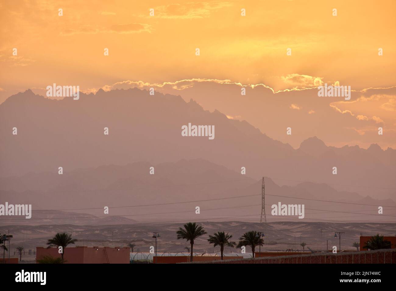 Sunset landscape with remote hotel complex against dark mountain peaks ...