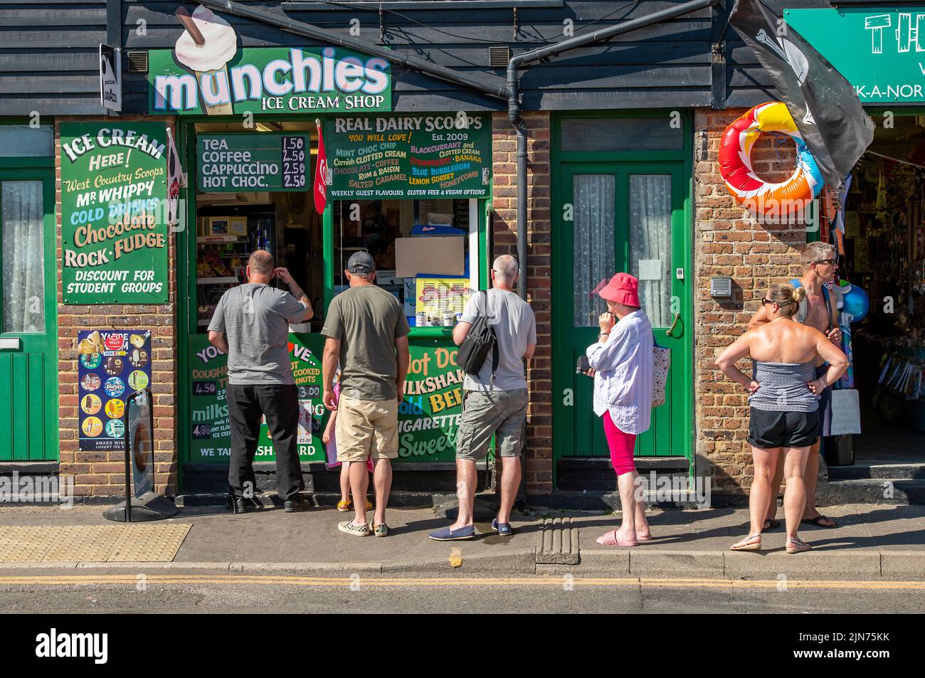 queue at an ice cream parlour in the summer sunshine at hastings in ...