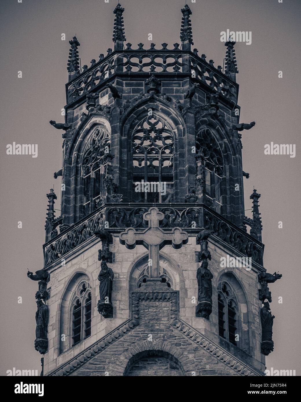 The vertical monochrome of the gothic church tower with a big cross ...