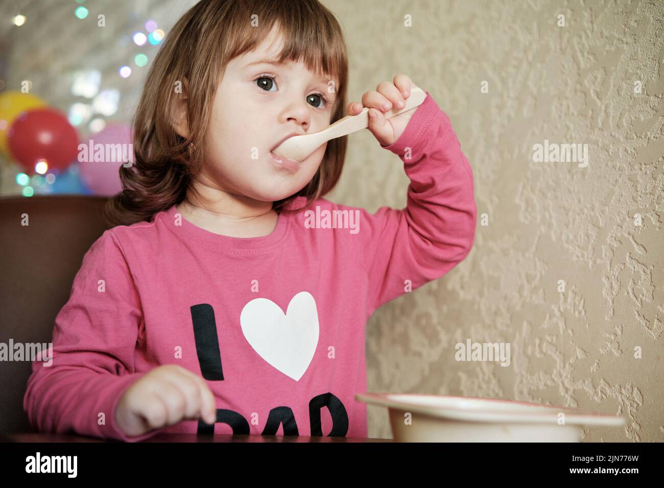 Cute Little Girl 2 Years alone eats porridge with a spoon. Child eat ...