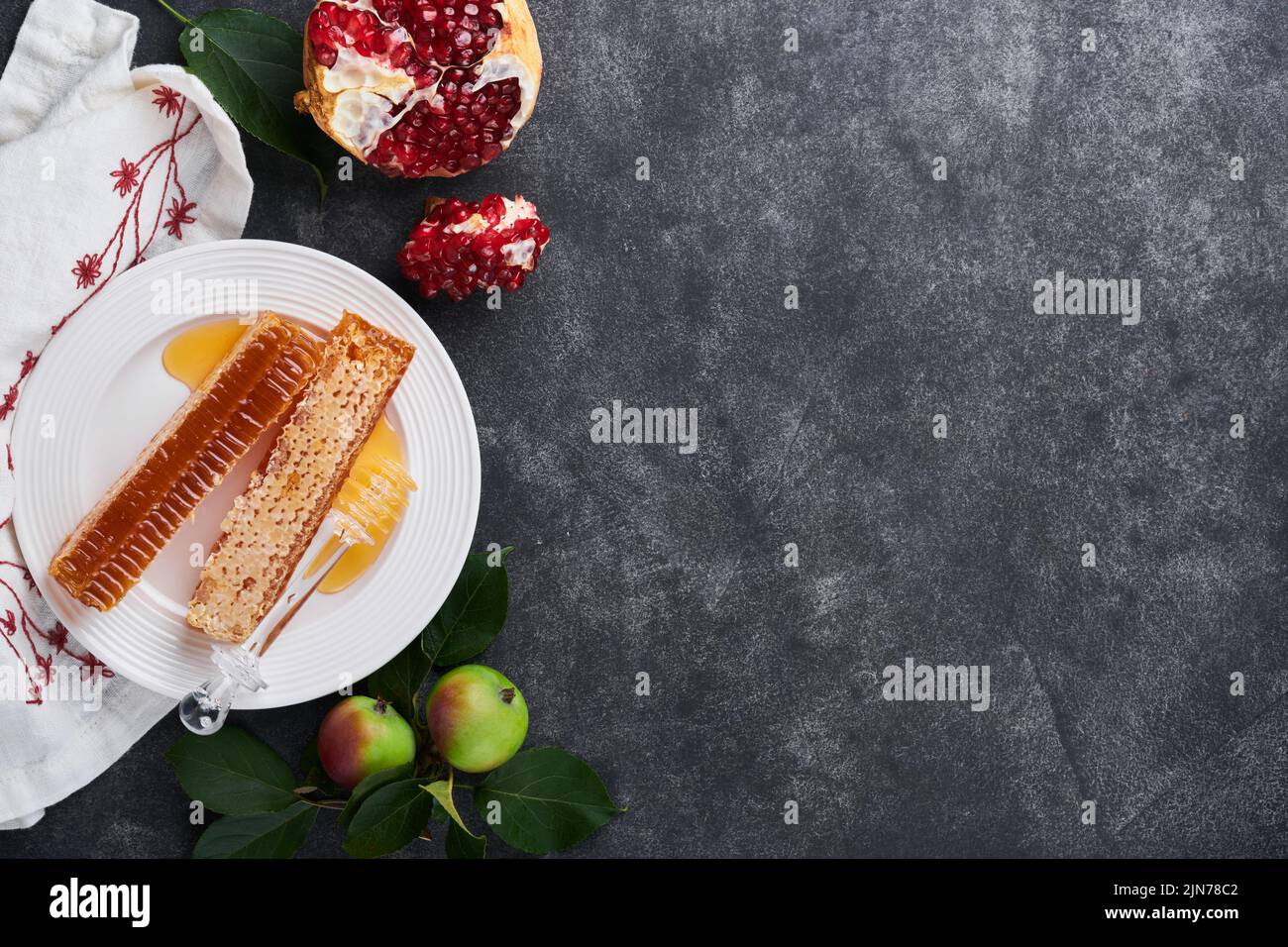 Rosh Hashanah. Honey jar, honeycomb, apple and pomegranate on dark grey ...