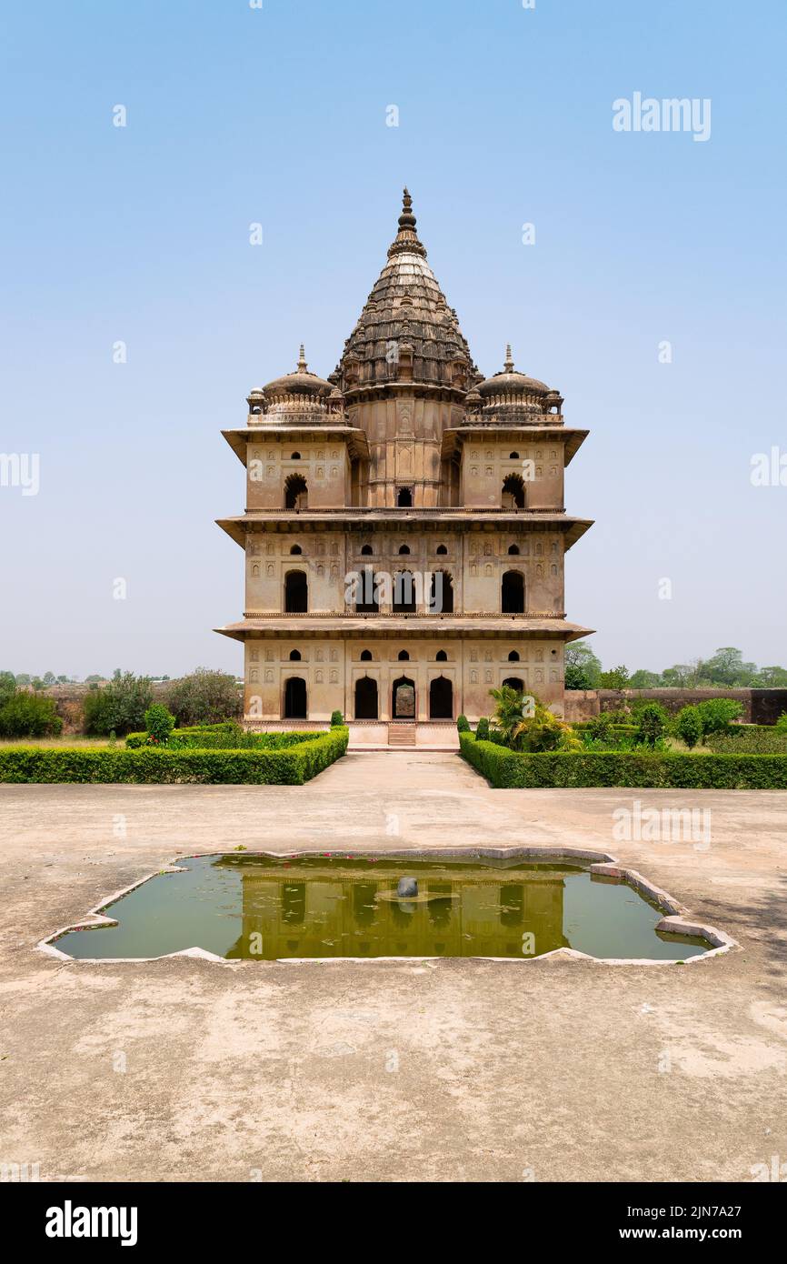 A vertical shot of the Royal Chhatris of Orchha and a pond with a ...
