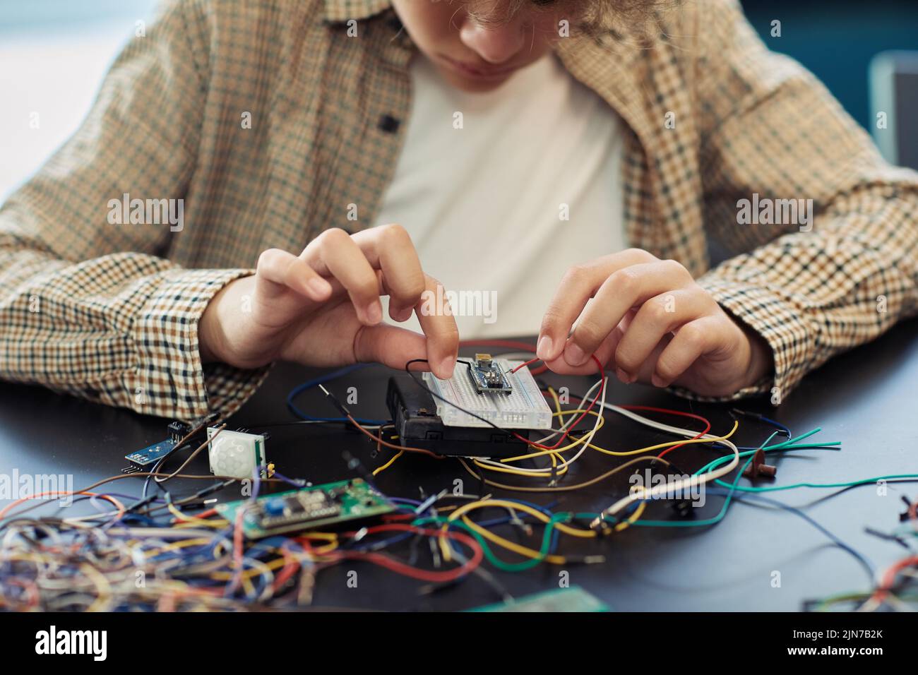 Close up of boy building robot and wiring circuit board during ...