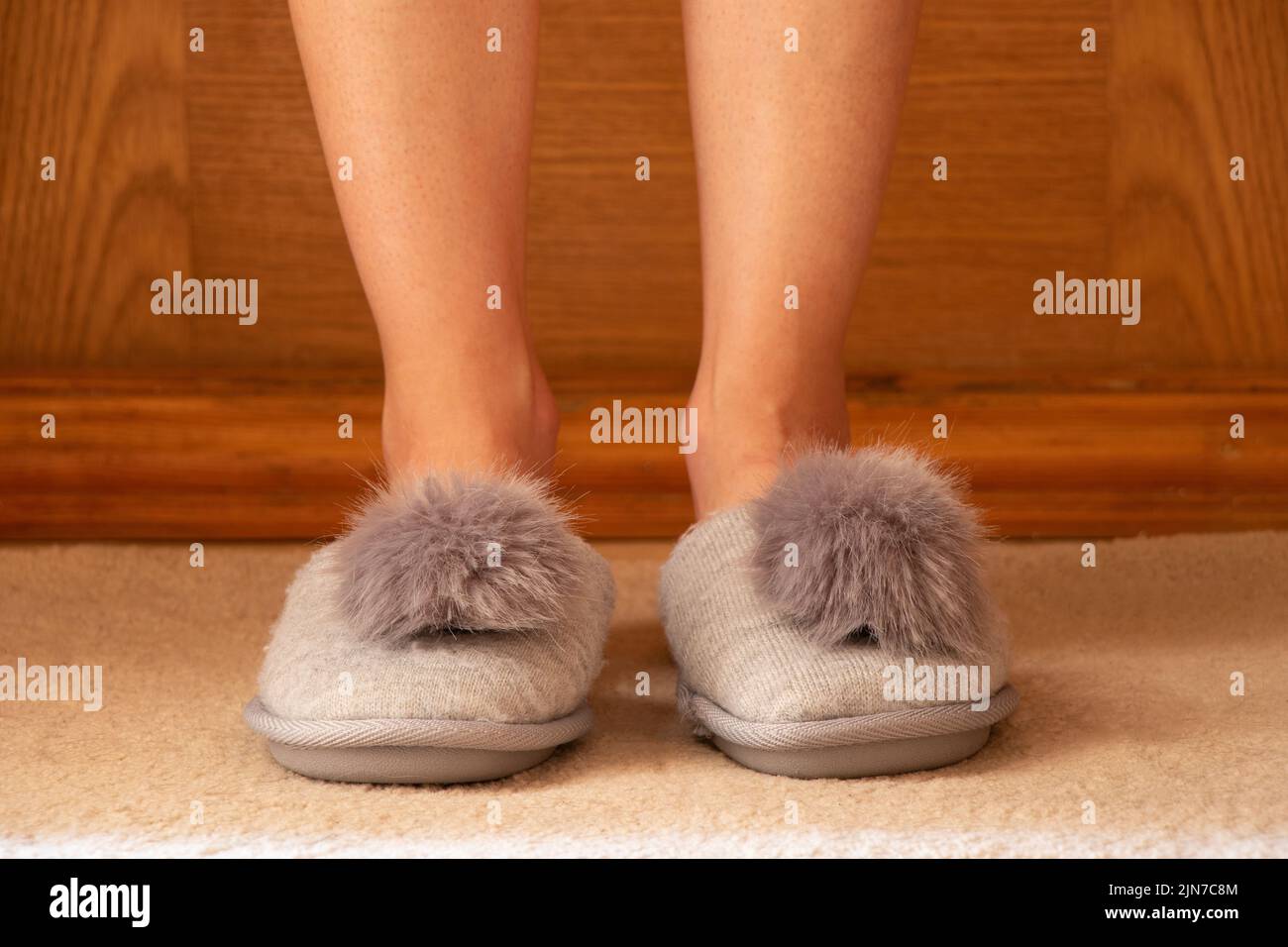 A girl in gray soft slippers with a bubo on the floor at home, home ...