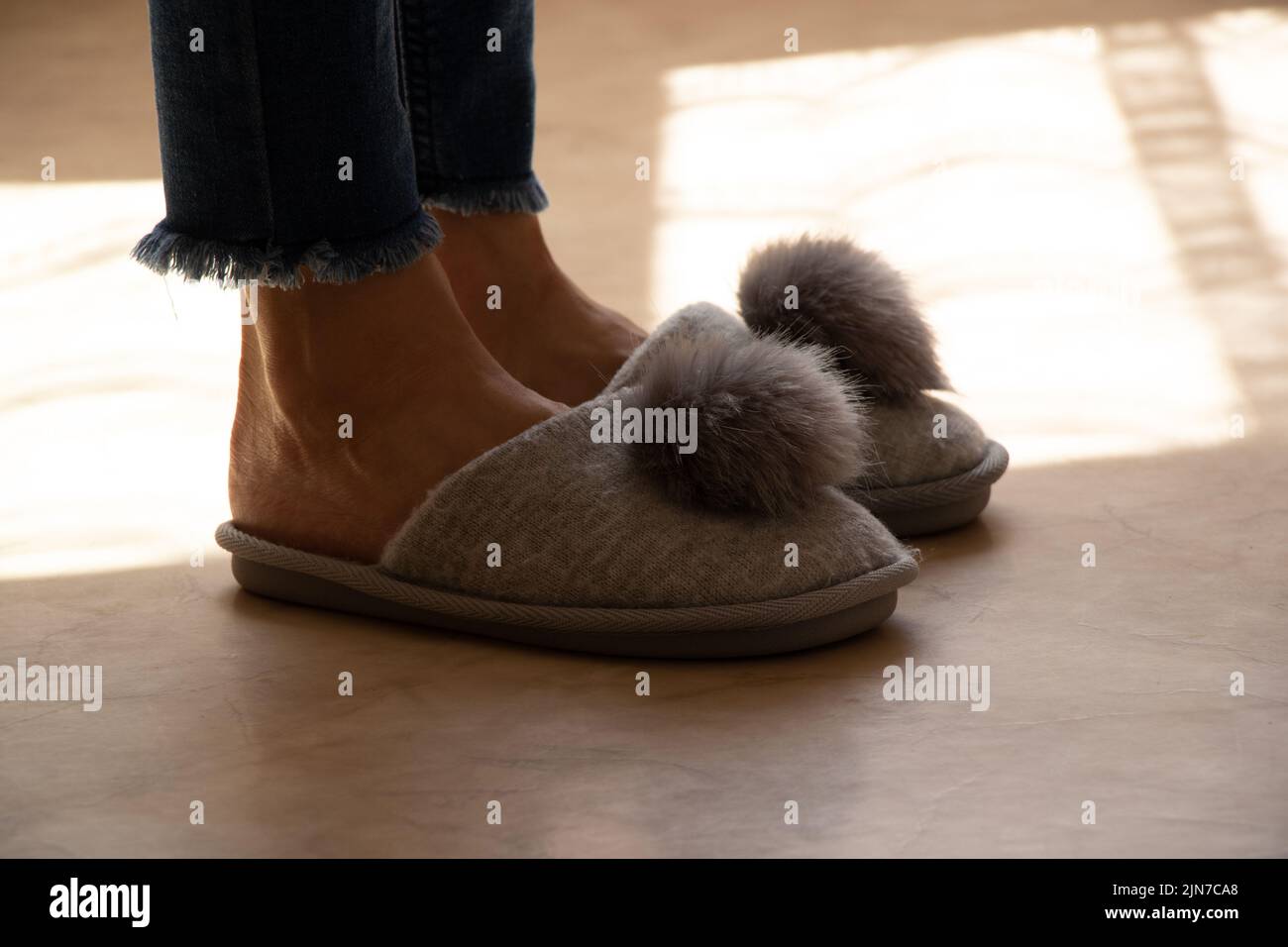 A girl in gray soft slippers with a bubo on the floor at home, home ...