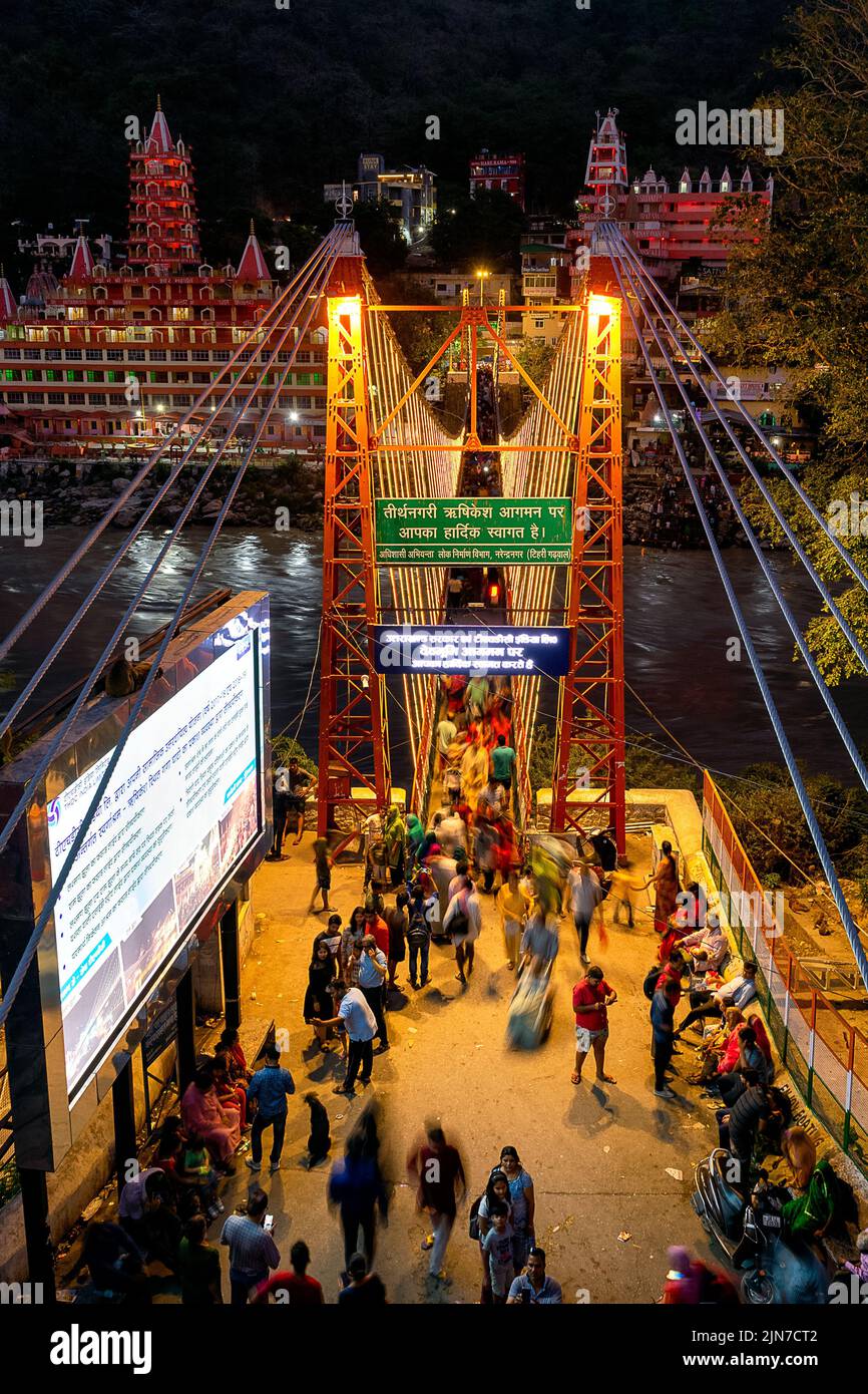 A vertical shot of the illuminated Rishikesh bridge and Ganges River in ...