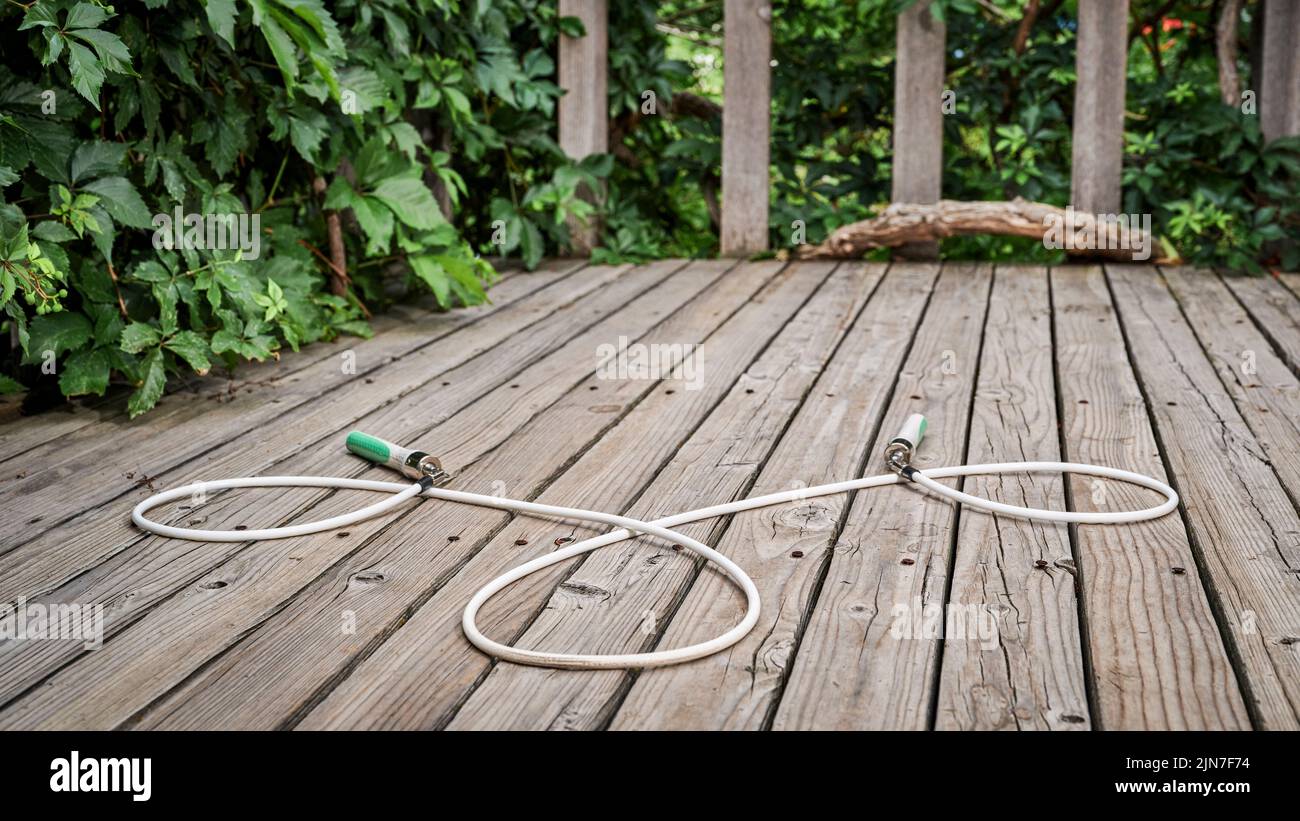heavy fitness jump rope on rustic, weathered wooden backyard deck Stock Photo - Alamy