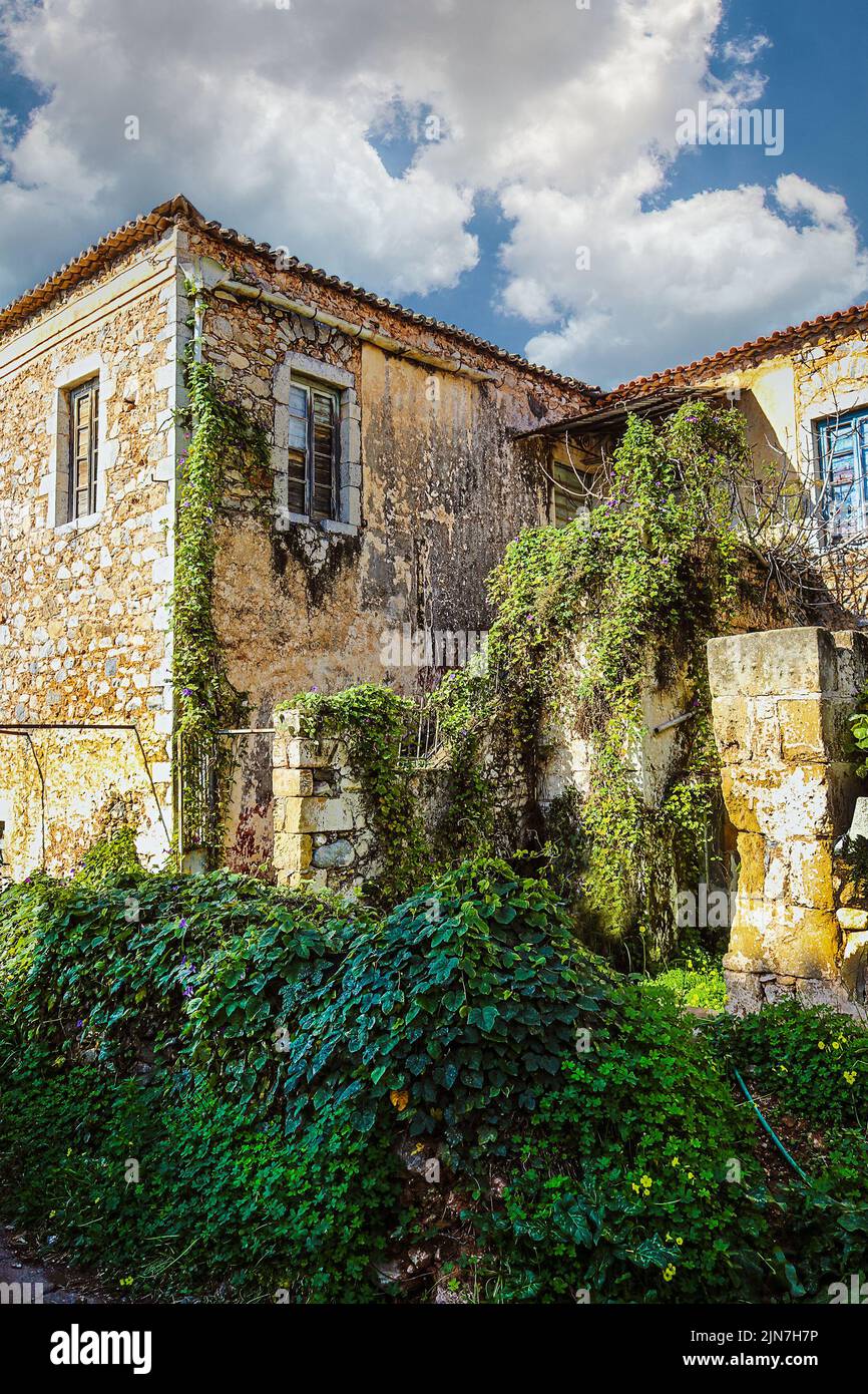 Two story ancient rustic rock and stucco building overgrown with vines ...