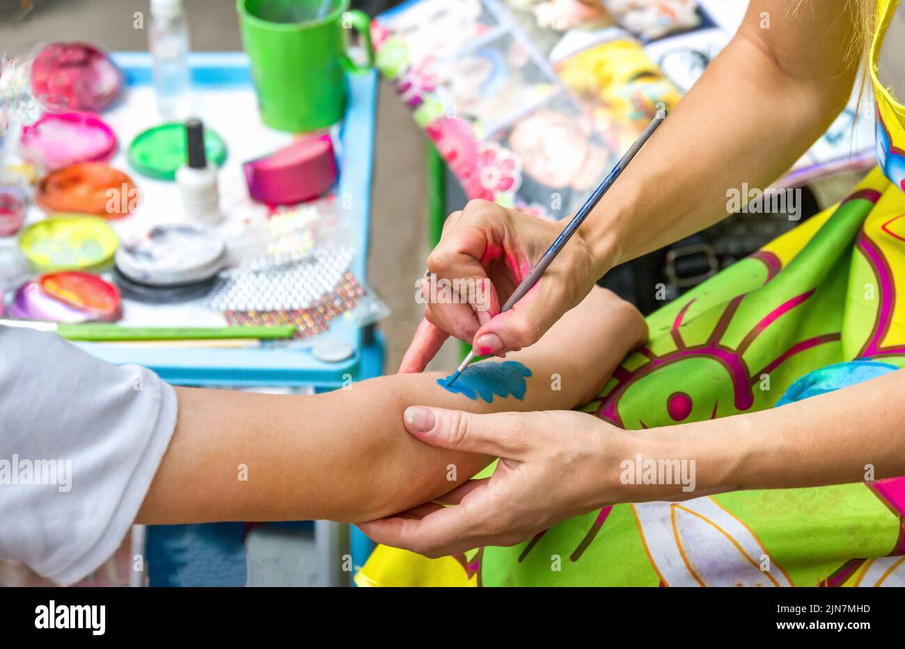 Woman artist draws drawing on child's hand. Painting skin with paints ...