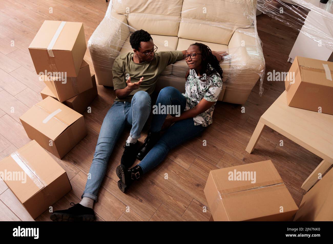 African american people sitting on apartment floor after moving in and ...