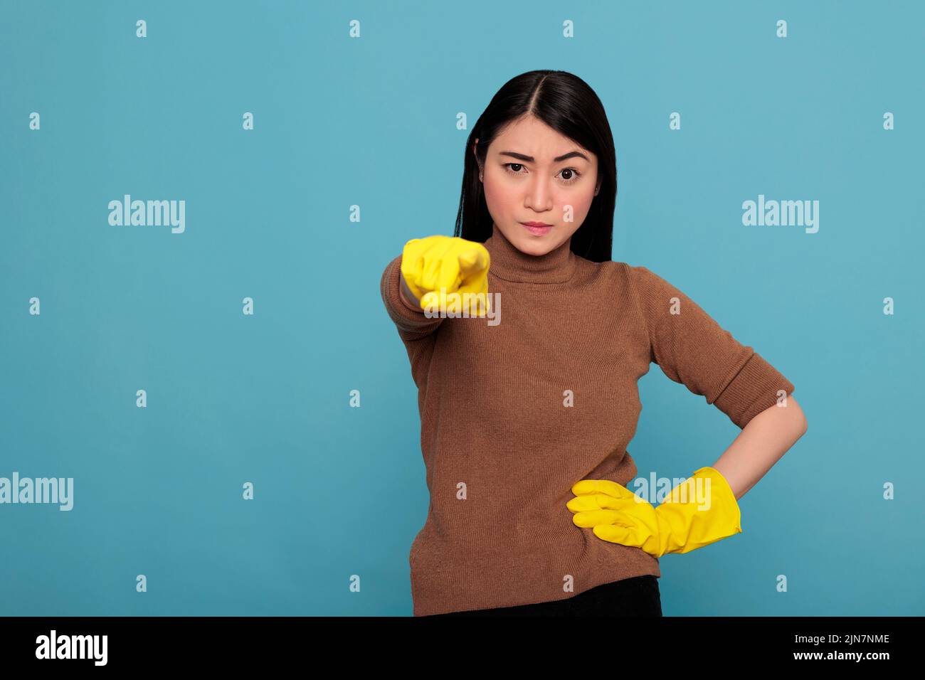 Angry sad and exhausted asian housemaid at work wearing yellow gloves ...
