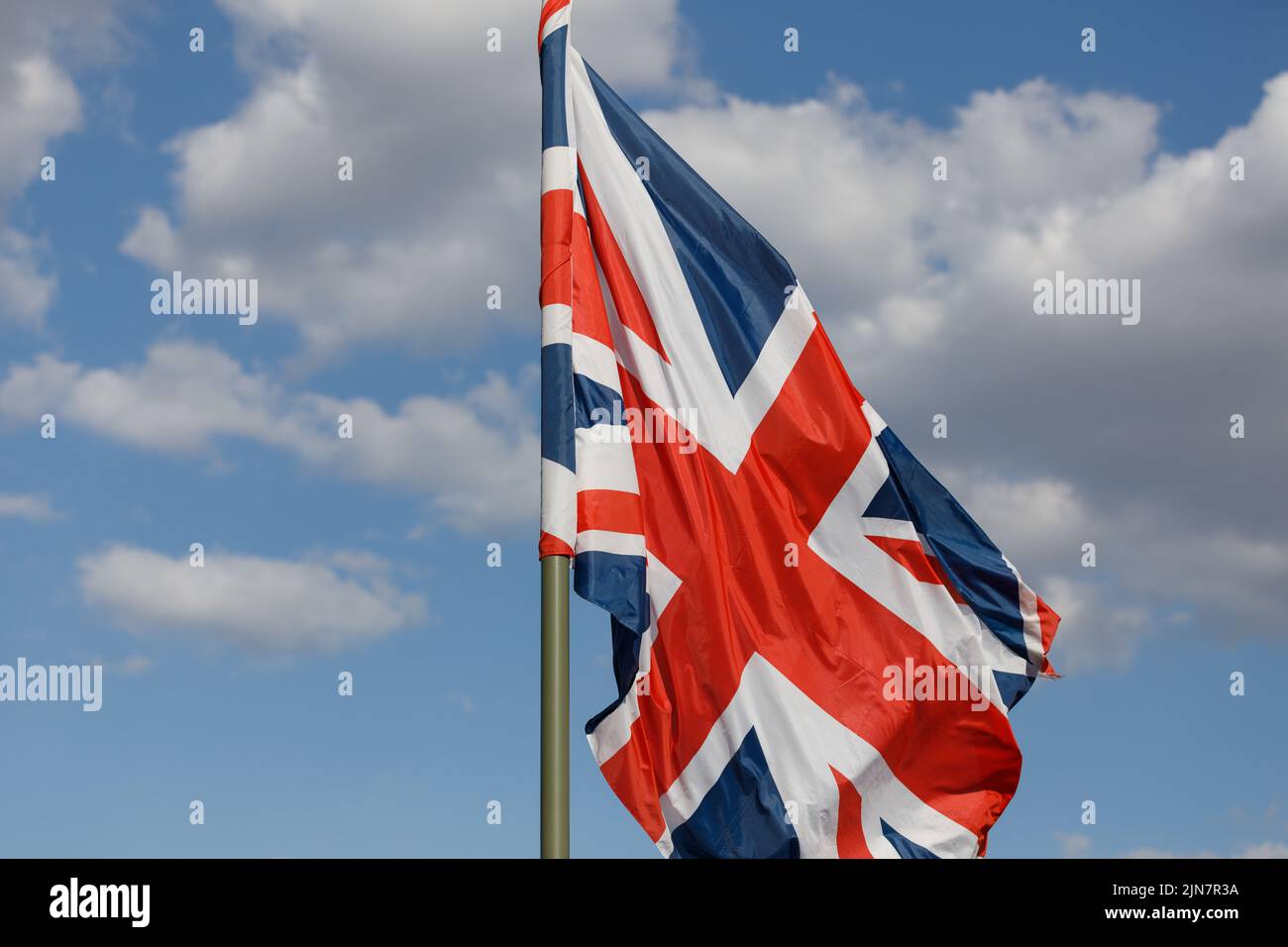 Union Jack flag on a blue sky background futtering in the wind. The ...