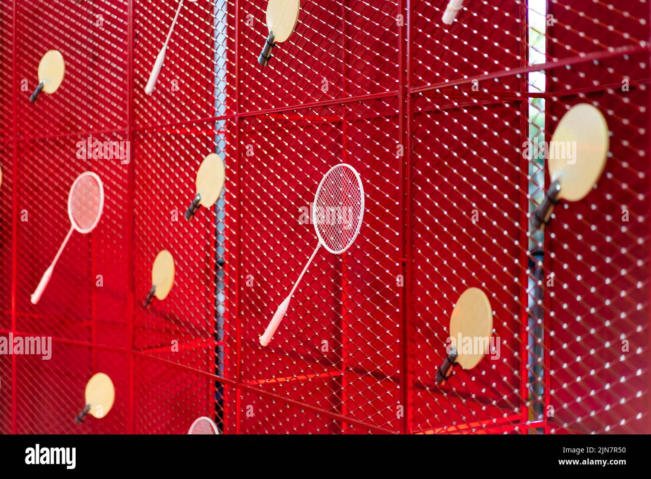 Table tennis and badminton rackets are hung on a red square grill steel ...