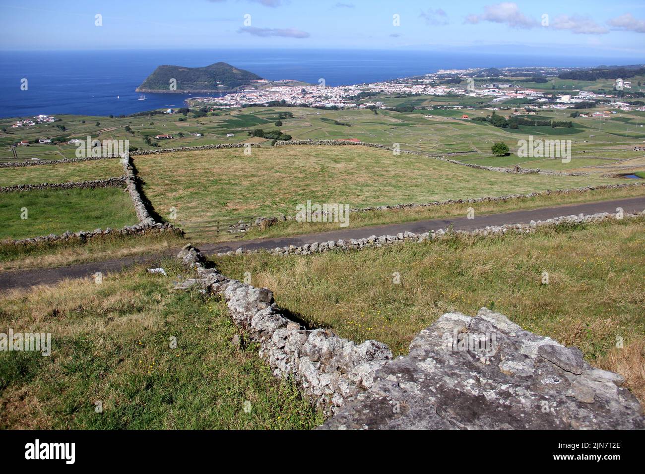Rural landscape, with green pastures and stone fences, sloping toward ...