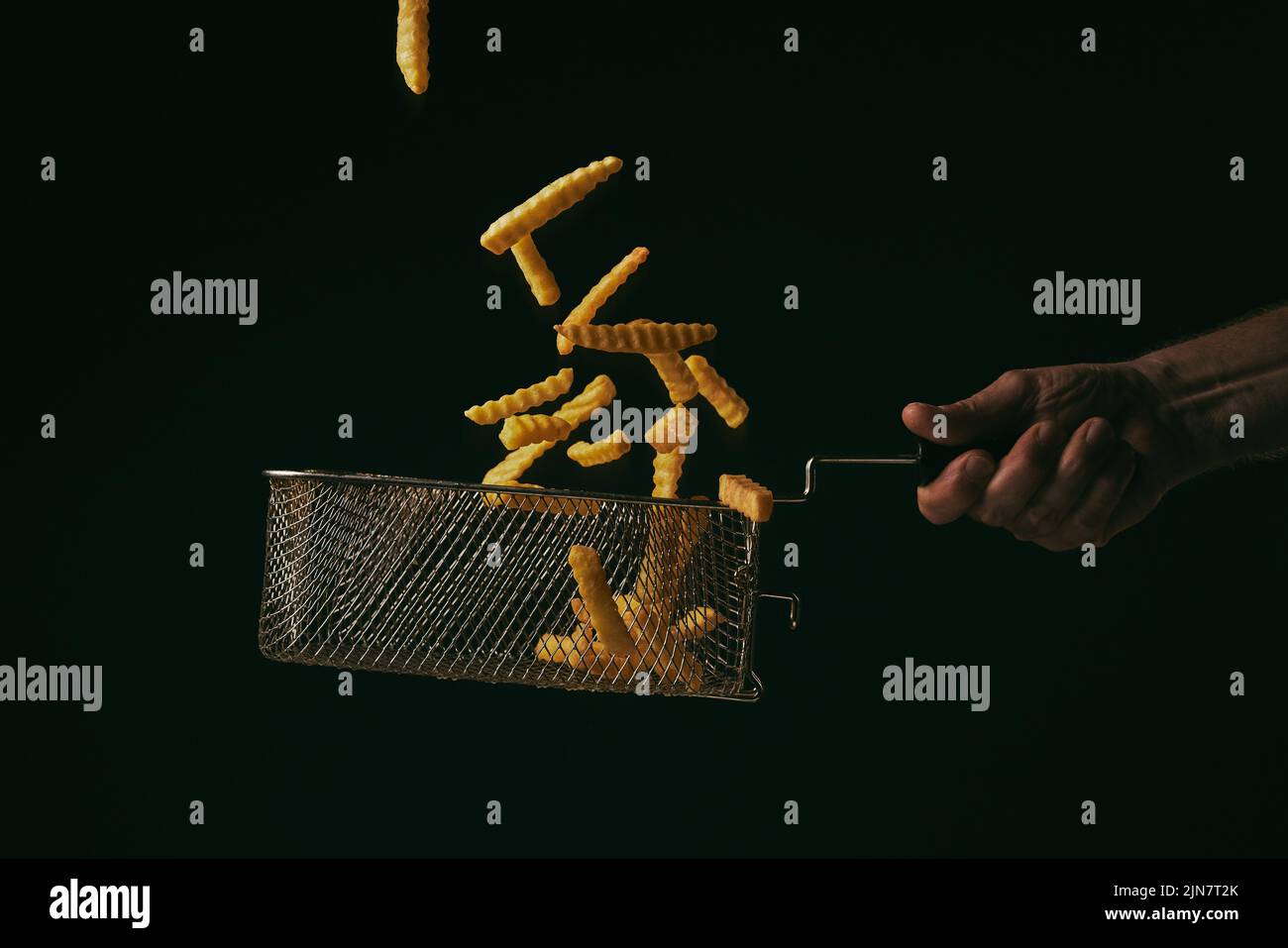 The fried potatoes flying out of a basket isolated on a black ...