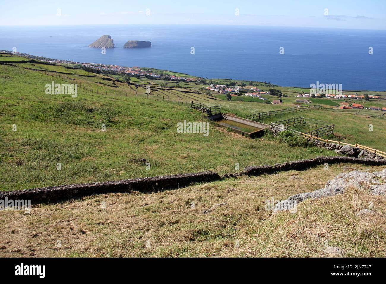 Rural landscape, with green pastures and stone fences, sloping toward ...
