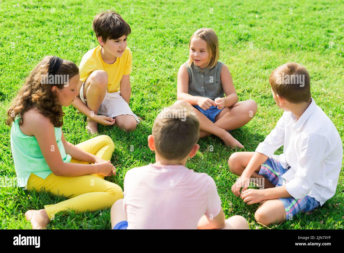 Children friends sitting on grass together and chatting Stock Photo - Alamy