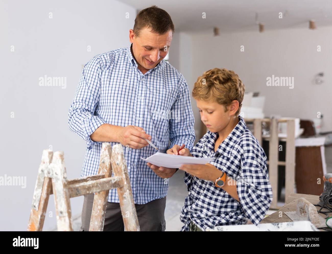 Father and his young son discussing work plan in construction site ...