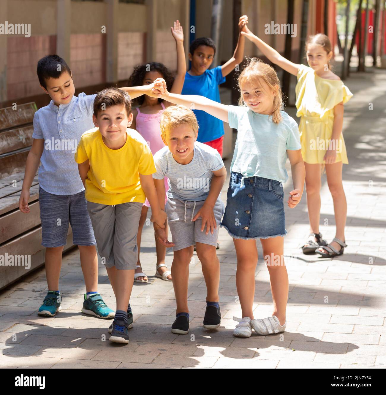 Group of positive schoolchildren holding hands up and playing Stock ...