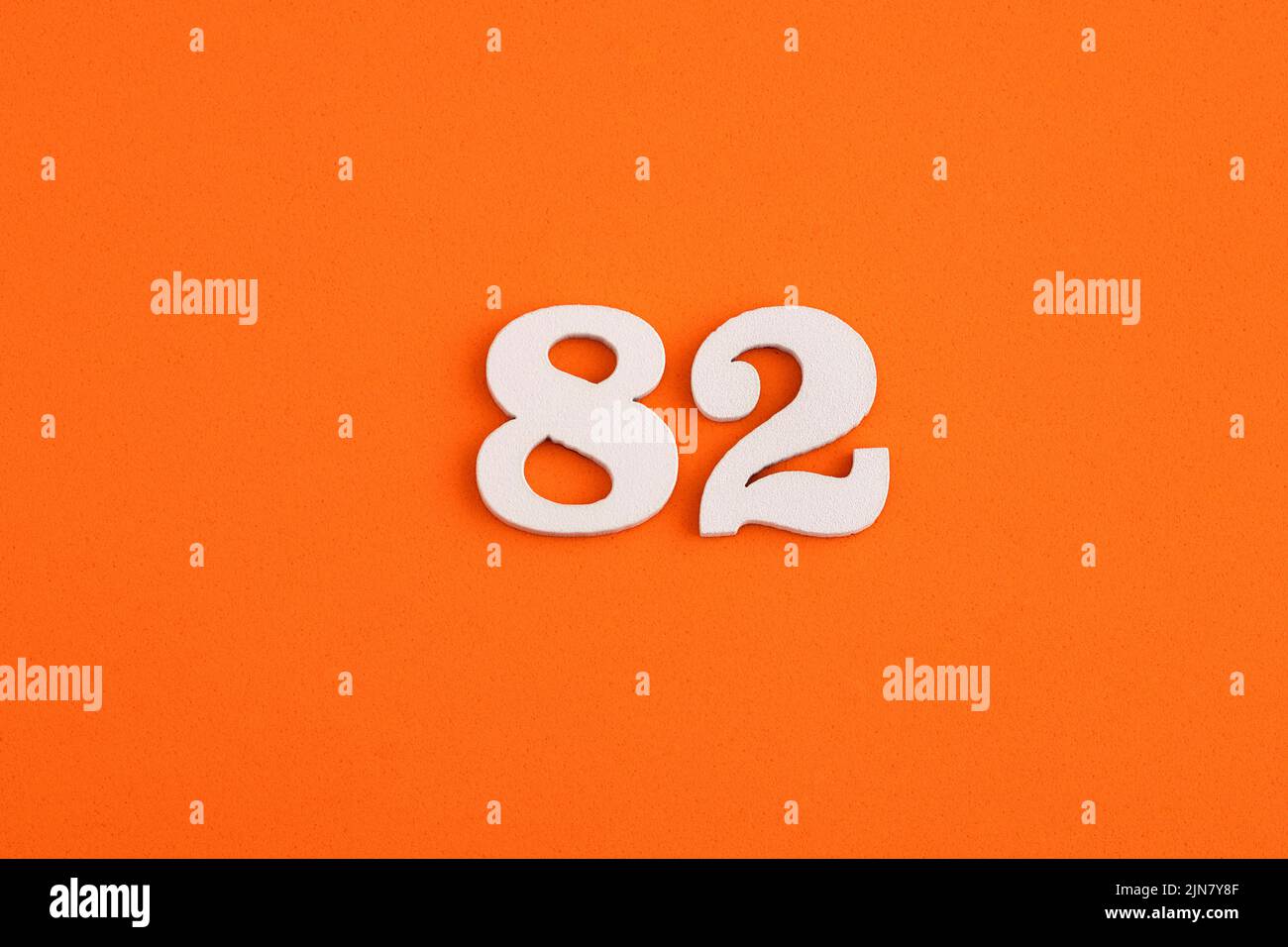 White wooden number 82 on eva rubber orange background Stock Photo - Alamy