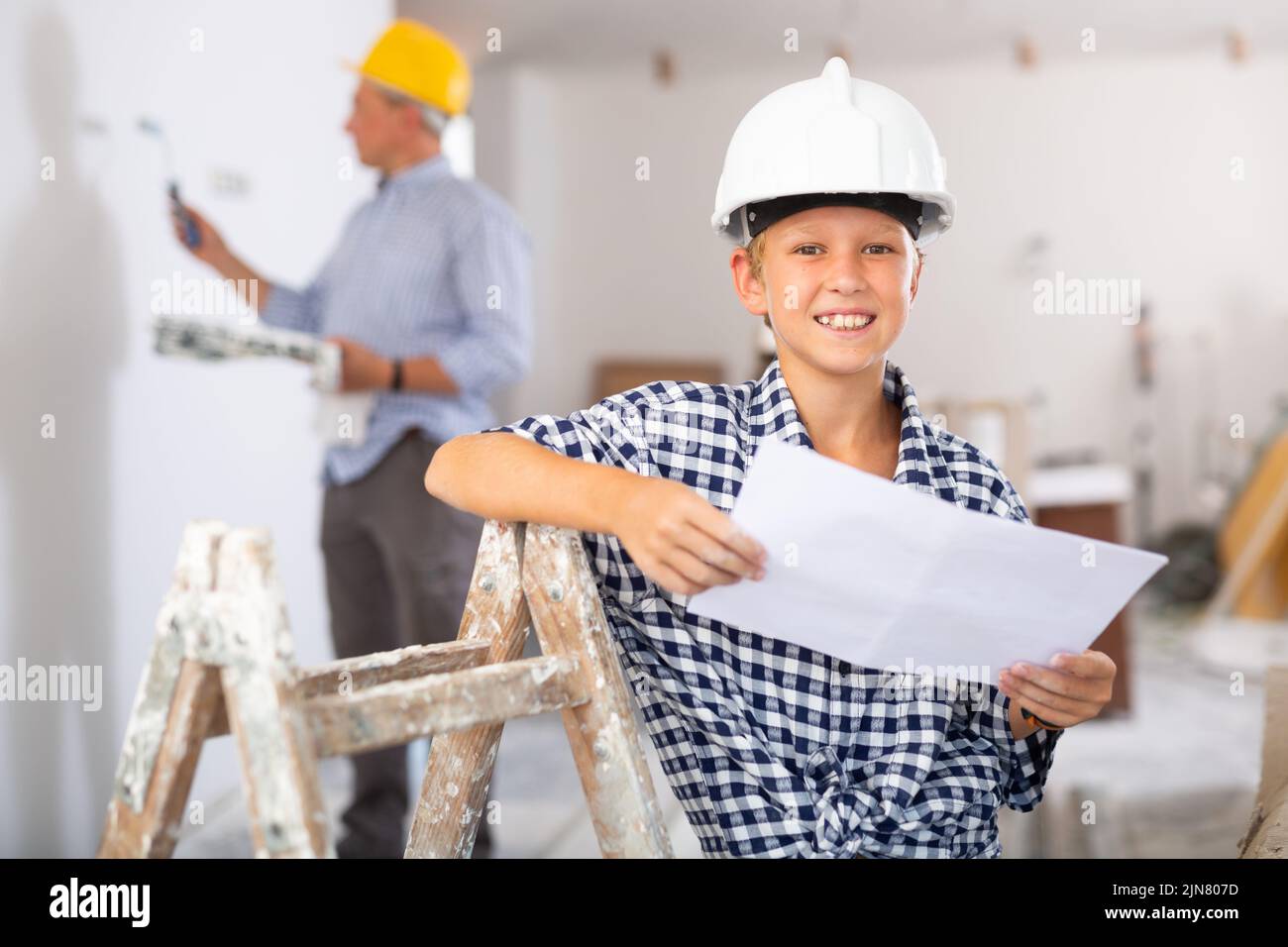 Portrait of builder boy checking blueprints in room being renovated ...