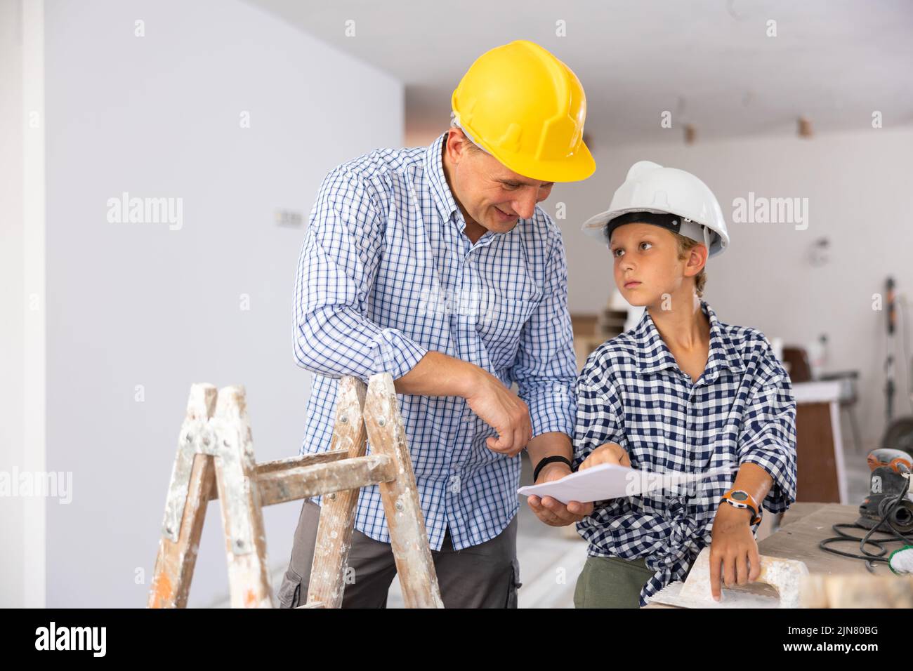 Father and his young son discussing work plan in construction site ...