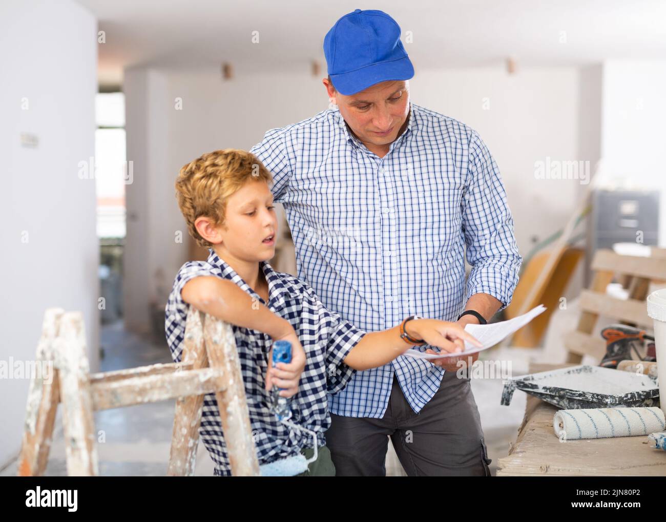 Father and his young son discussing work plan in construction site ...