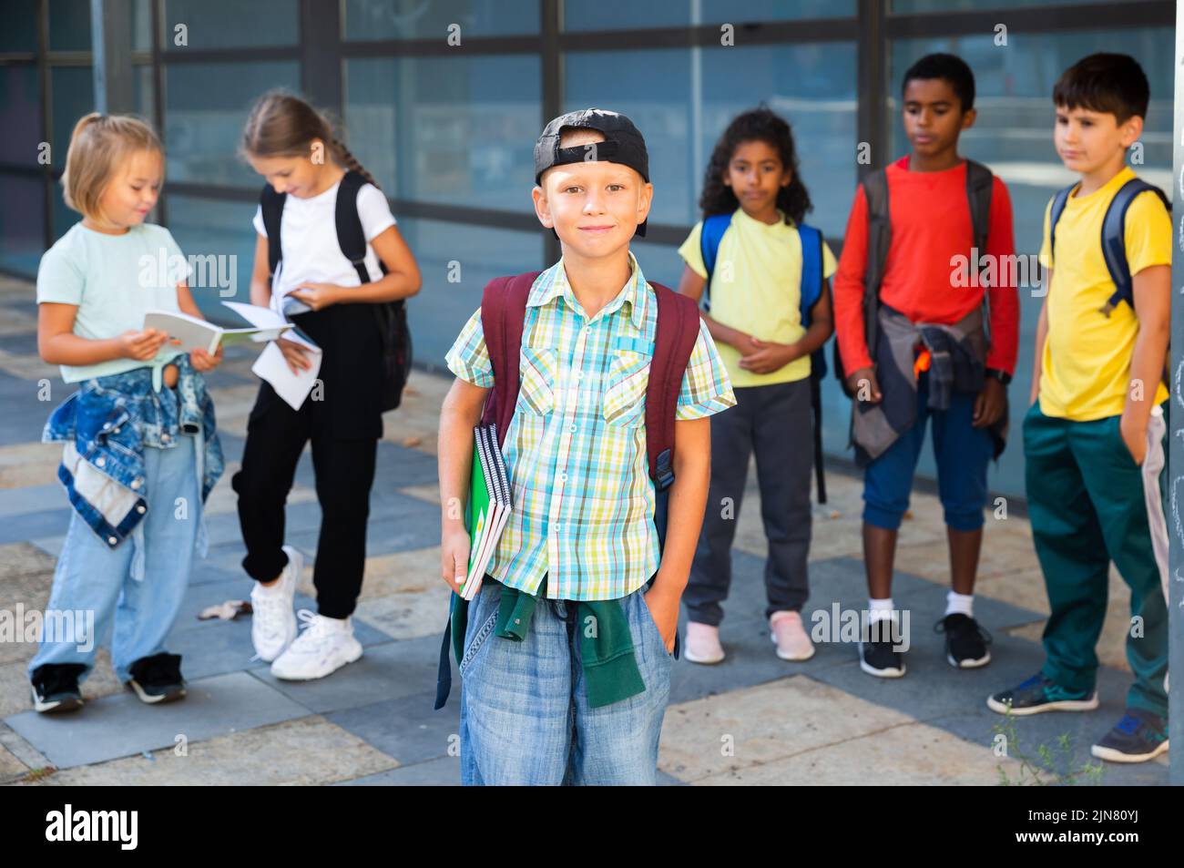 Cheerful tween boy standing in school campus with notebooks Stock Photo ...