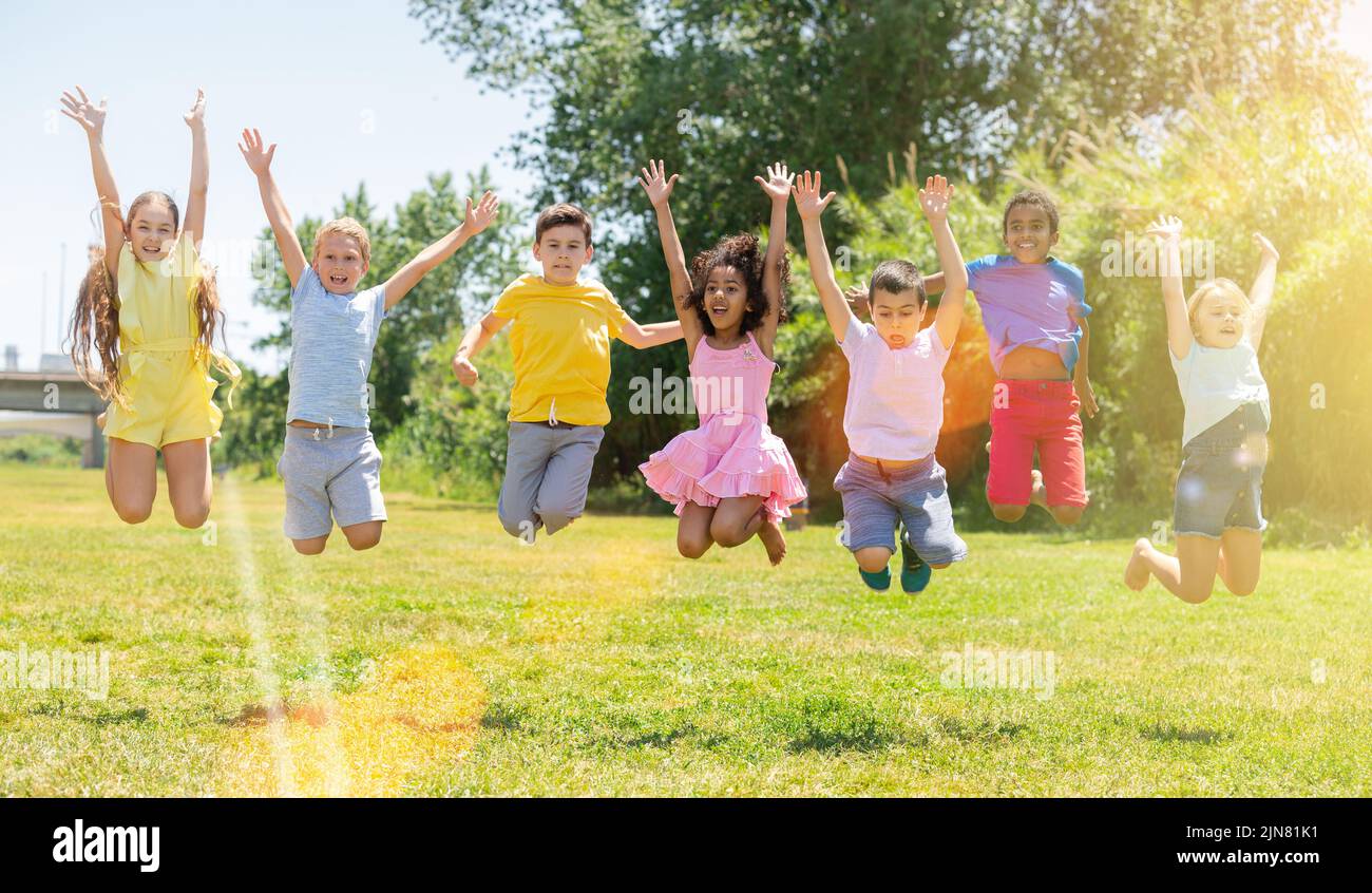Schoolchildren jumping and smiling together in park Stock Photo - Alamy