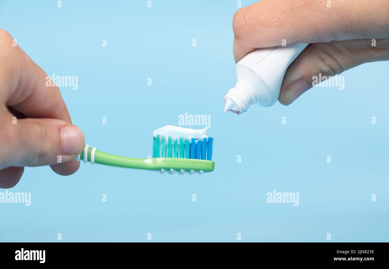 toothpaste is applied to the toothbrush,tooth brushing in hand on blue ...