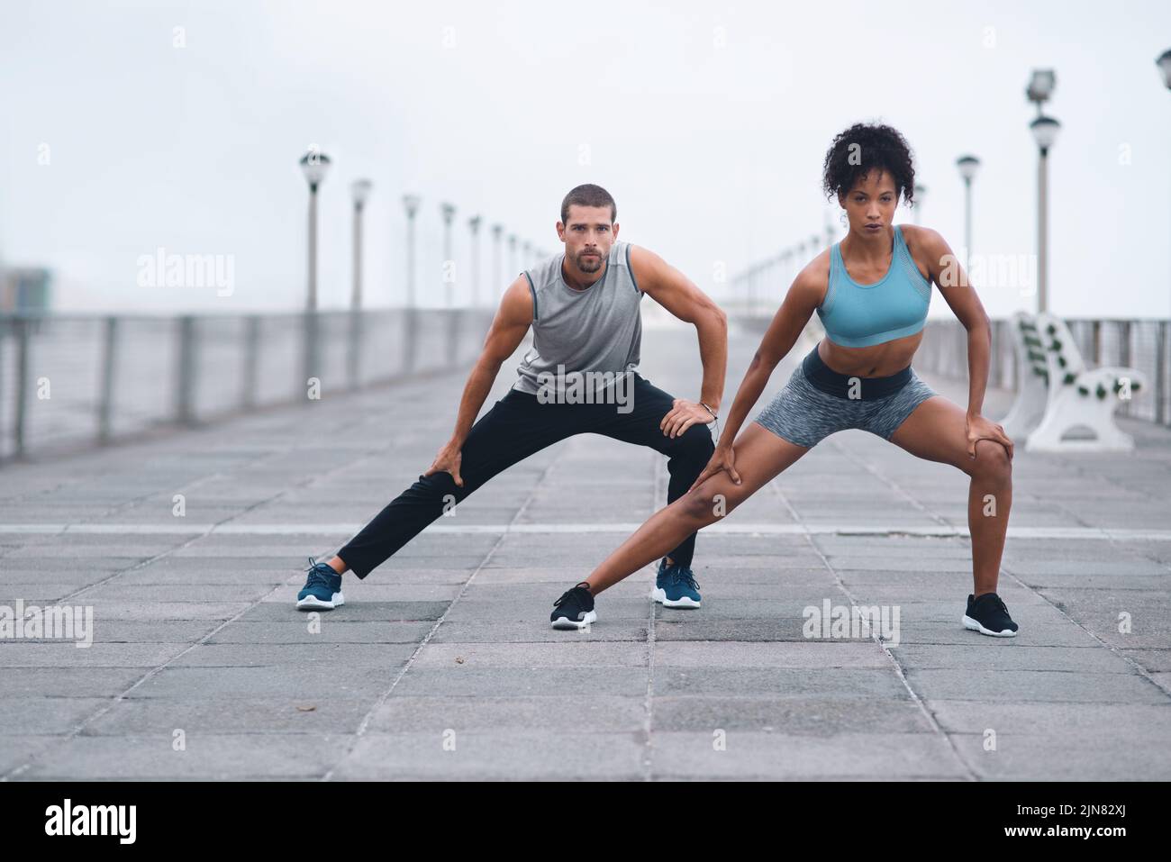 Stretch and hold. two sporty young people stretching while exercising ...