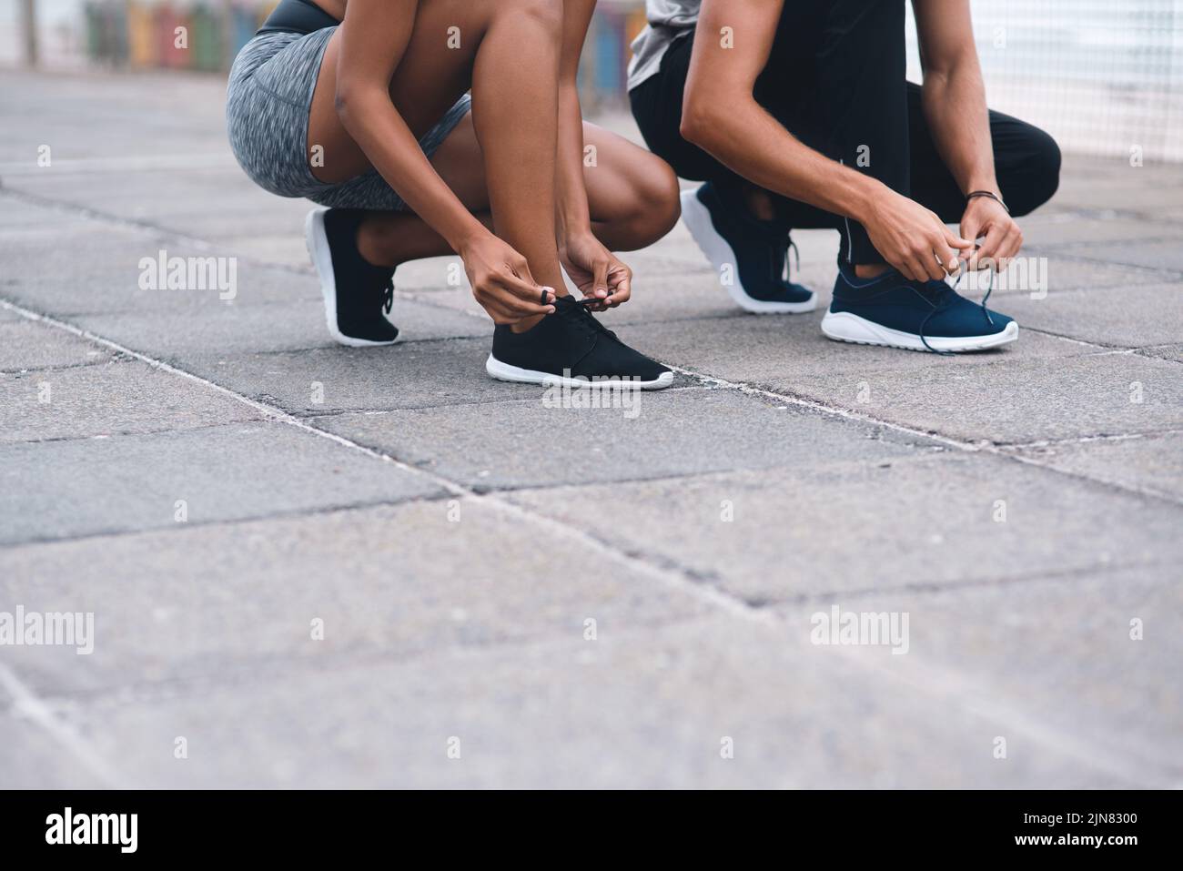 Theres no chance to trip this up. Closeup shot of two unrecognisable people tying their laces ...