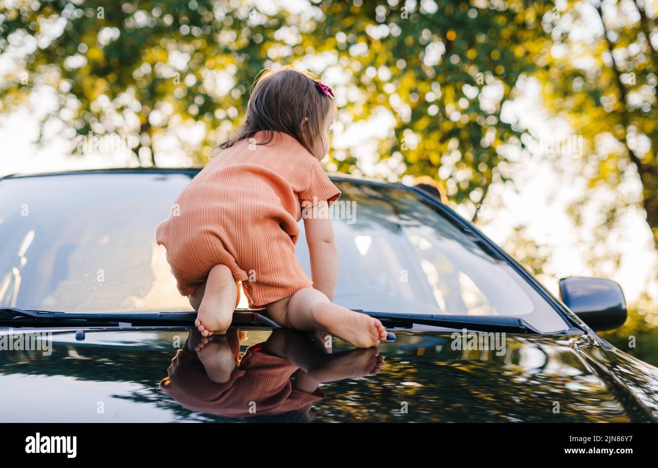 Baby girl crawling on car bonnet. Summer nature. Happy family ...