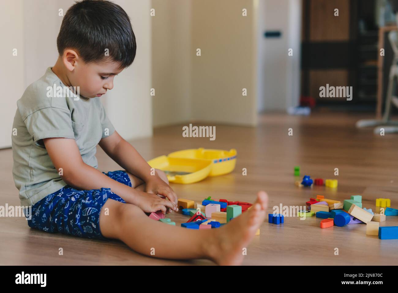 Boy building a tower of cubes, sitting on the floor at home. Concept of ...