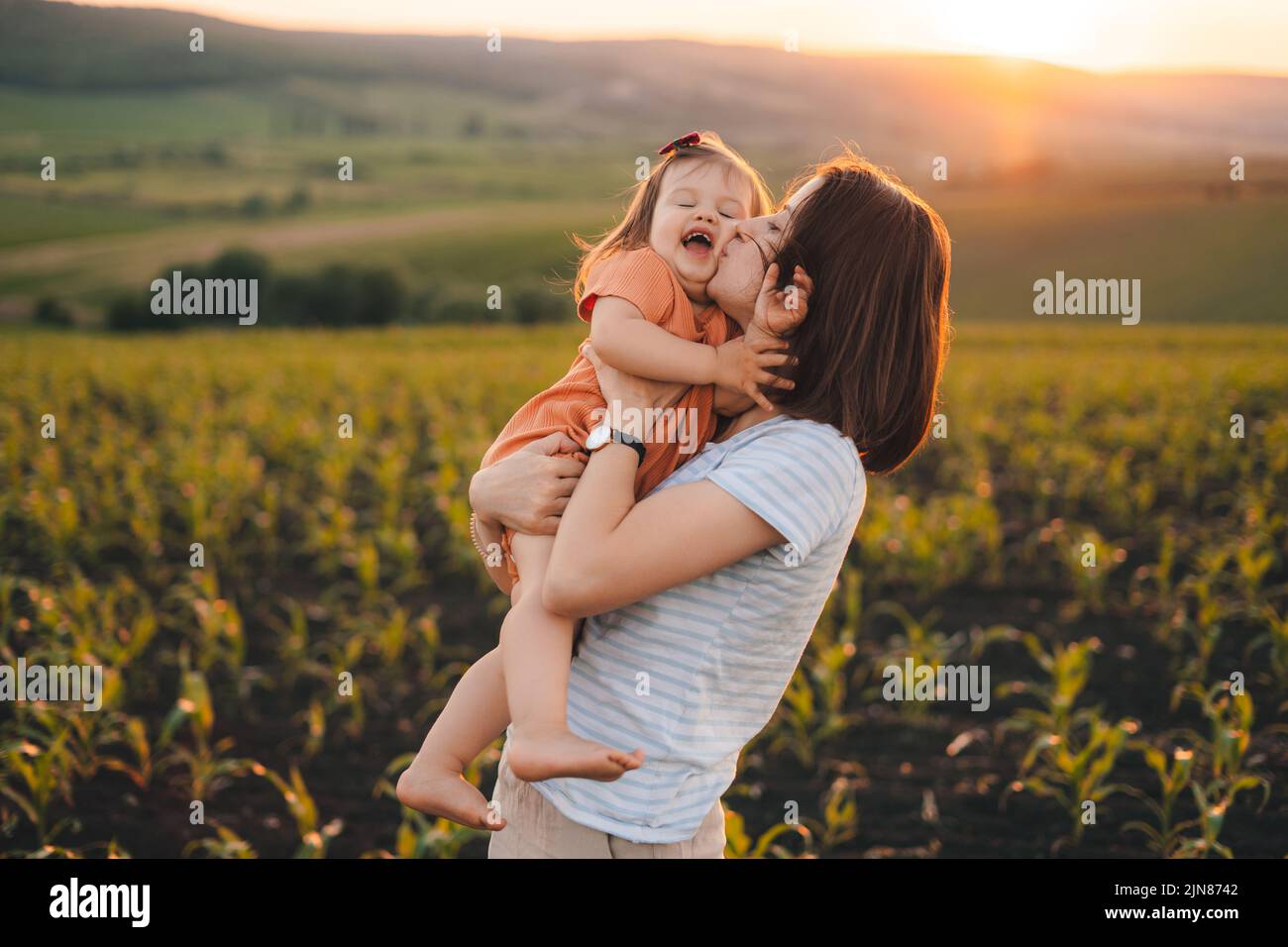 Portrait of a caucasian young mother and her daughter in a corn field ...