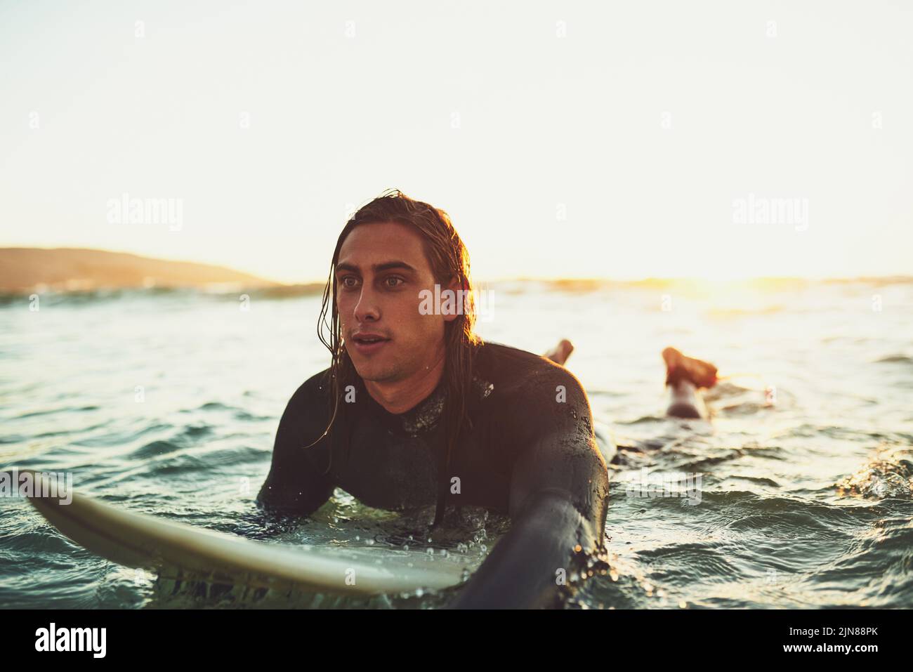 Ride with the tide. a young man paddling on a surfboard in the sea ...